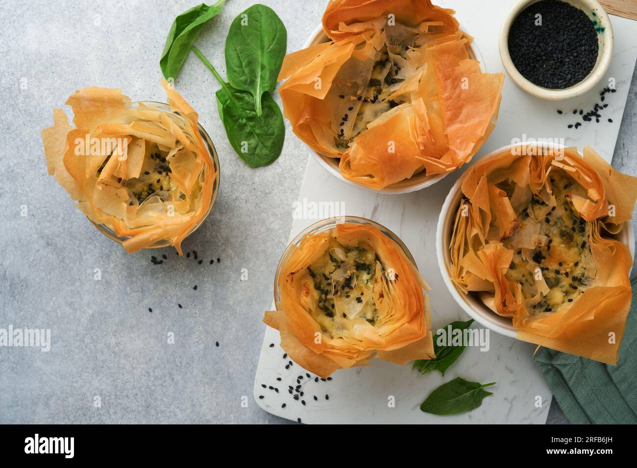 Filo pies with soft feta cheese and spinach in ceramic molds on old ...