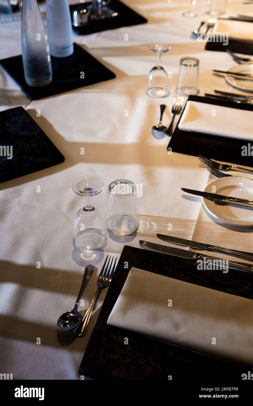 A large dining table set out with place settgings ready for a large ...