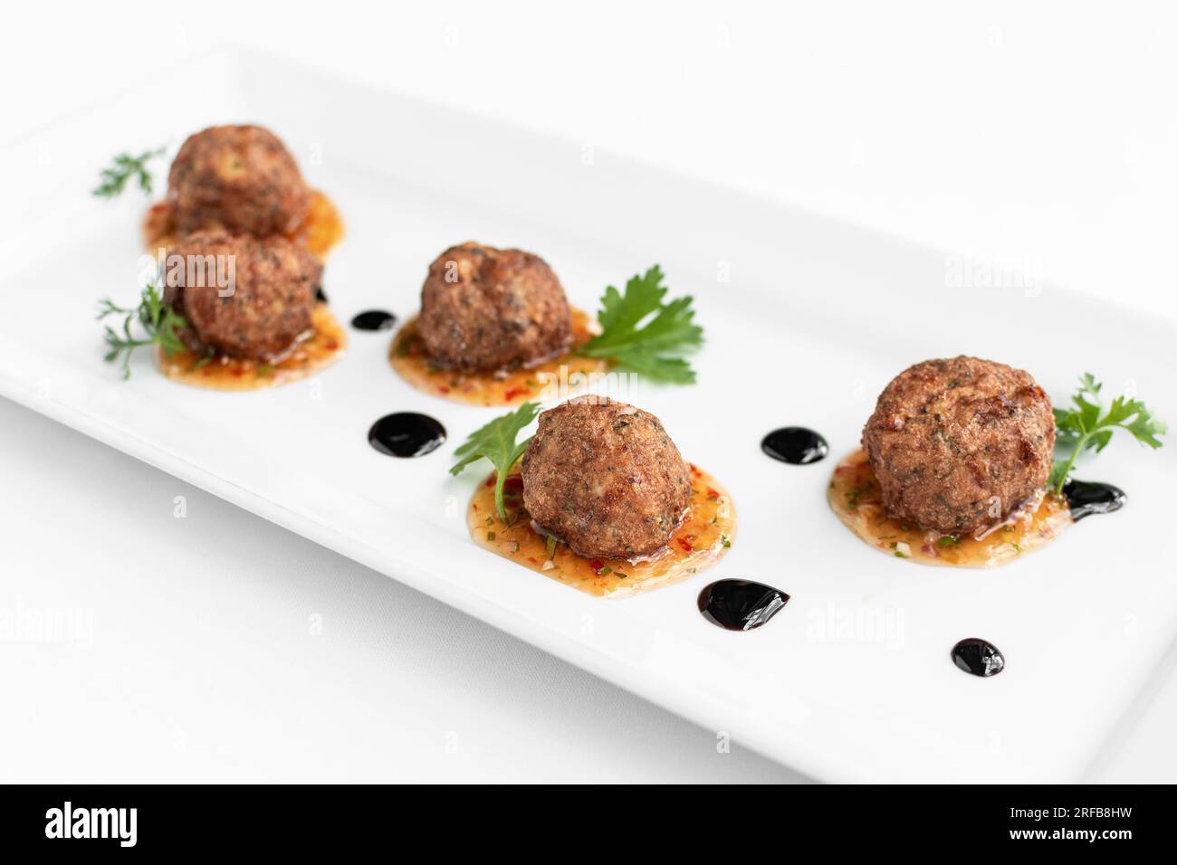 thai fish cake balls in gourmet contemporary restaurant on white plate ...