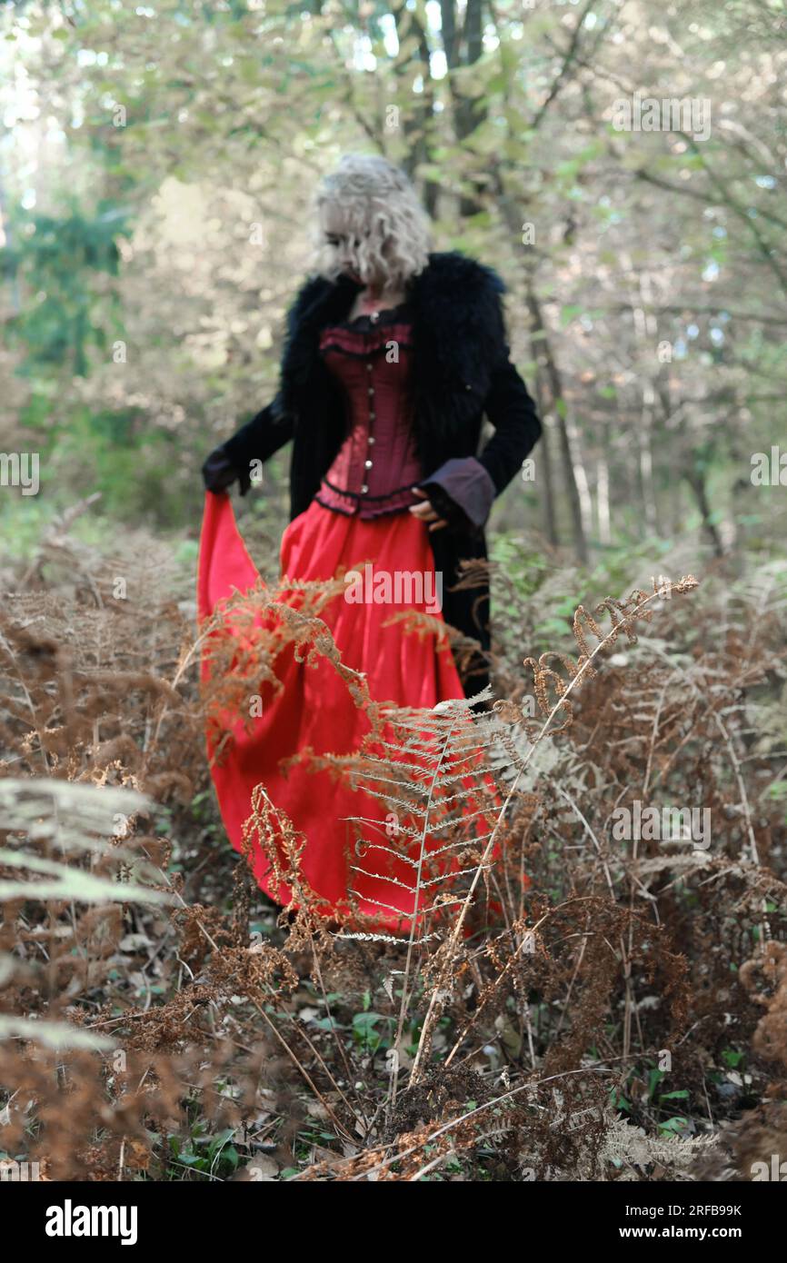A woman in the form of a vampire or a witch in a medieval dress walks ...