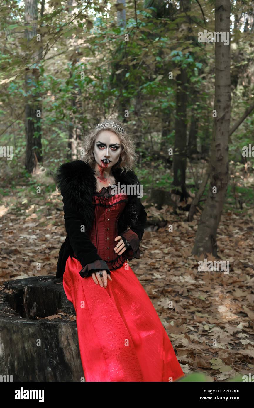 A woman in the image of a vampire or a witch with white make-up and in ...