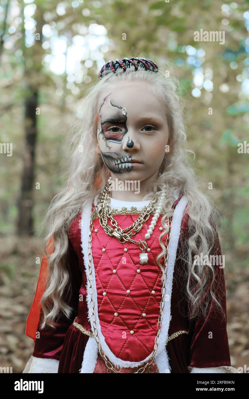 A child girl poses in a forest in a medieval dress in the image of a ...