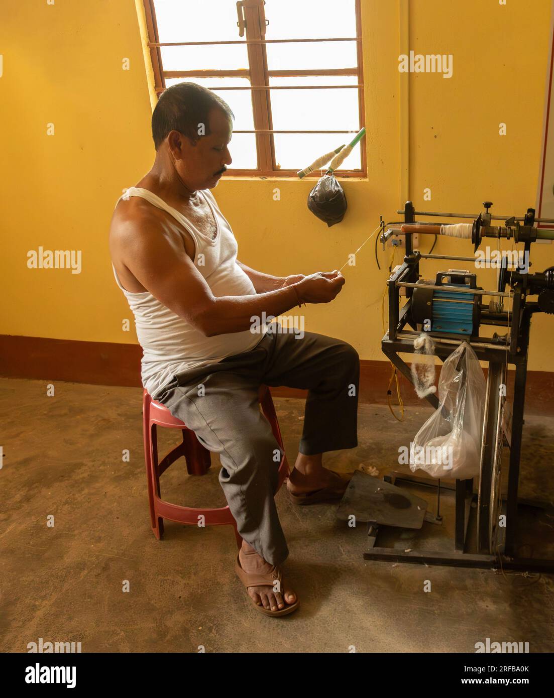 Man demonstrating how to spin silk into threads in Sualkuchi, a small ...