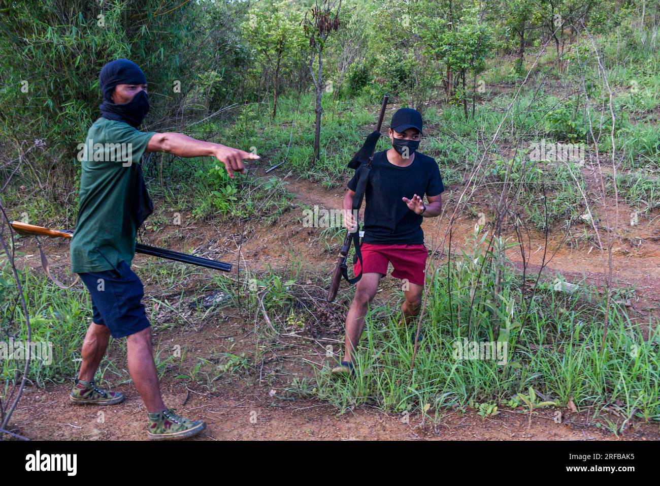 A squad leader trains a youth how to hide during enemy attacks in the ...