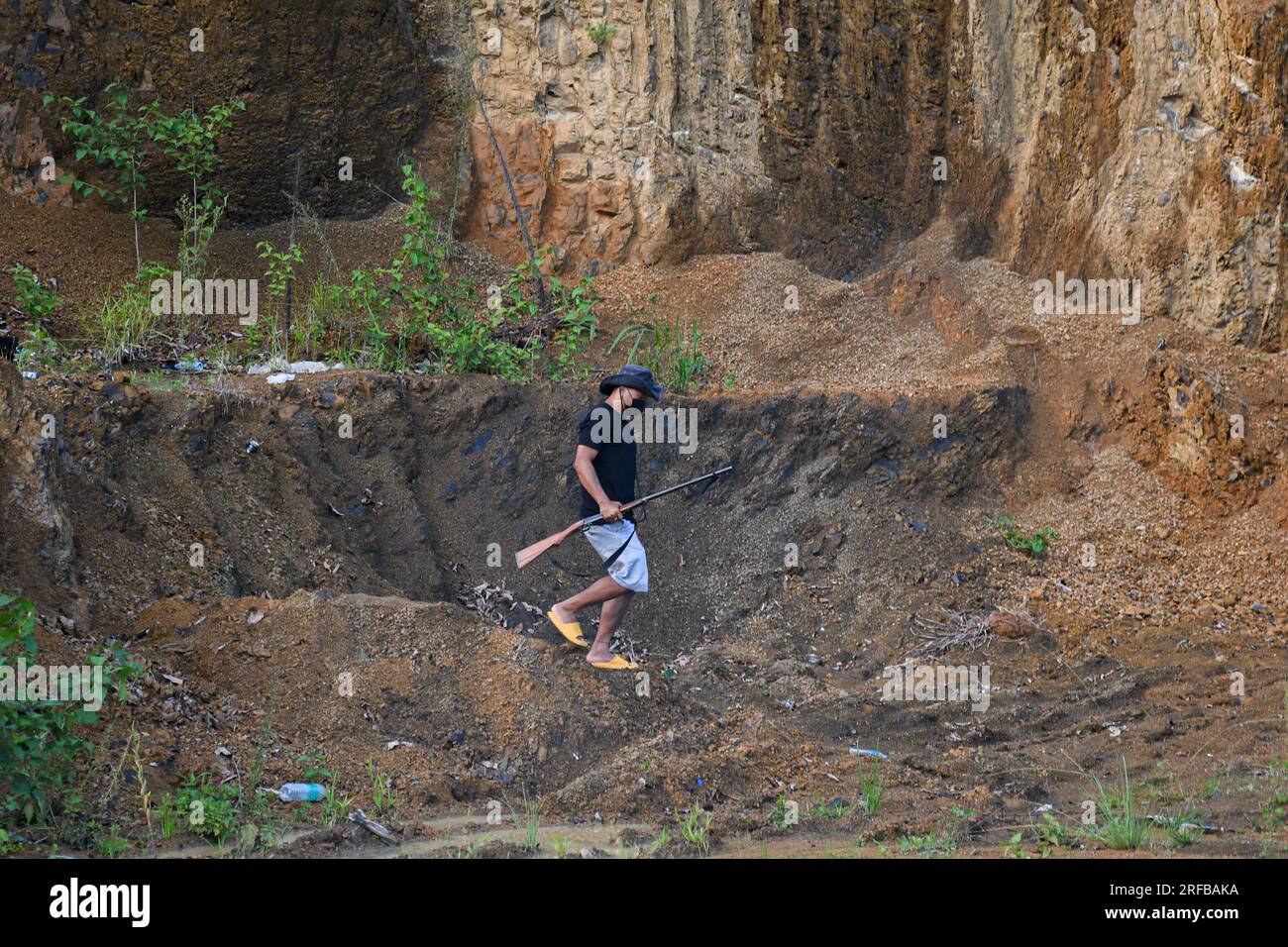 An armed Kuki man walks on a mountain path during a training program in ...