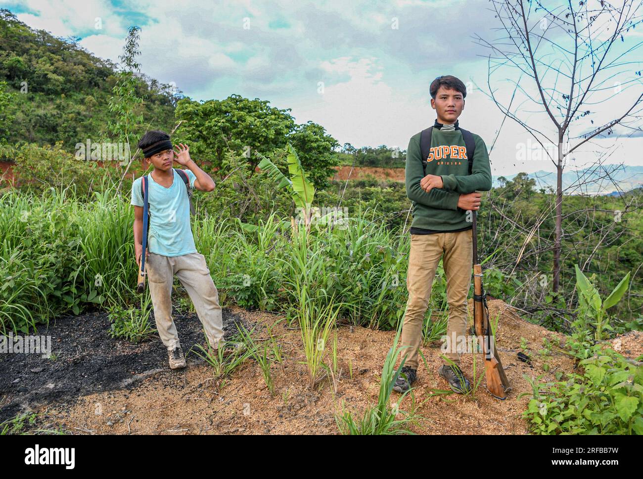 Armed Kuki boys react to the camera as they wait for their friends near ...