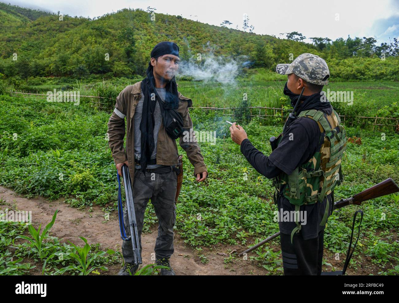 Armed Kuki men smoke a cigarette together while guarding the Dampi ...