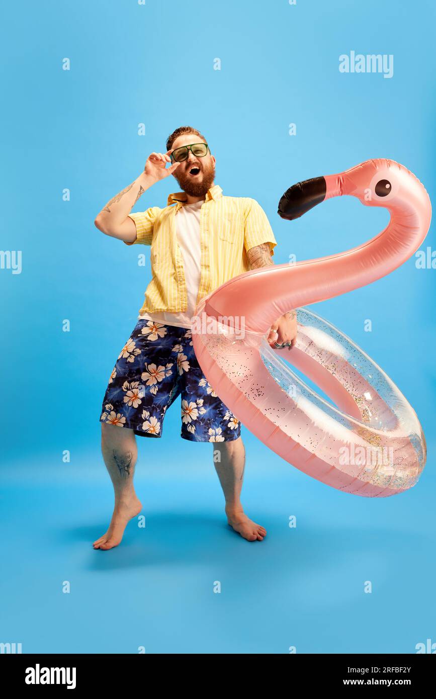 Happy and relaxed bearded man in swim shorts and yellow shirt standing ...