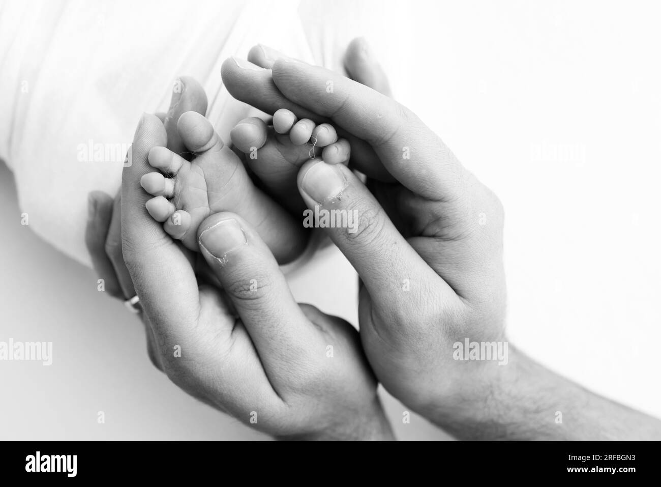 The palms of the father, the mother are holding the foot of the newborn ...