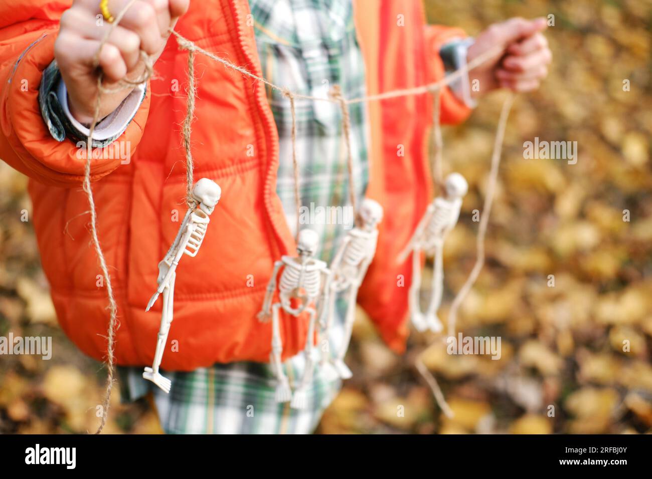 Decorative Skeletons hang on a rope in a children hands Stock Photo - Alamy