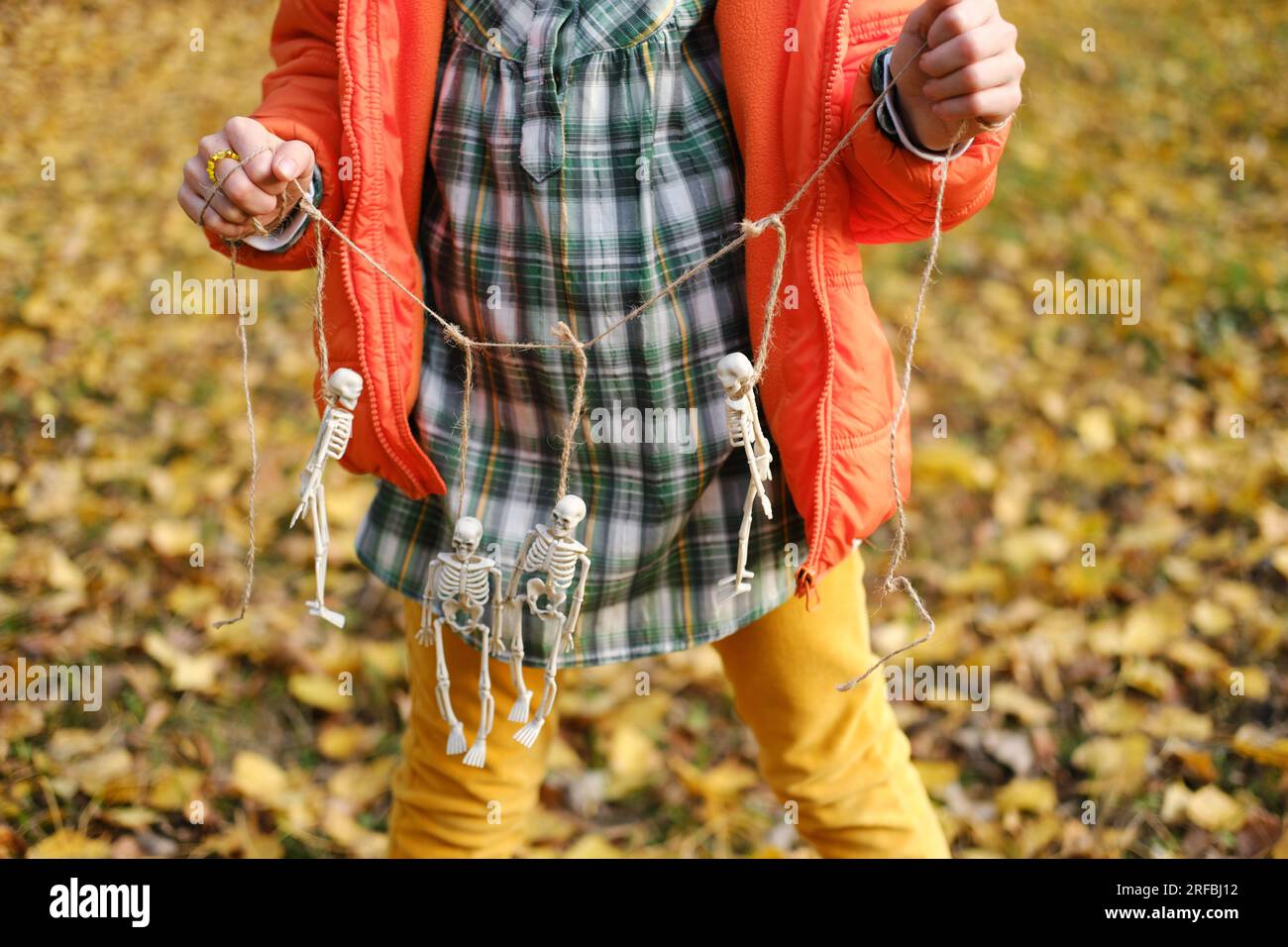 Decorative Skeletons hang on a rope in a children hands Stock Photo - Alamy