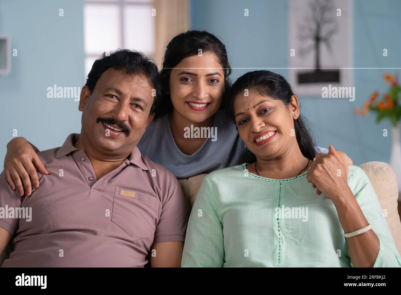 Happy middle aged parents with Adult daughter looking at camera while ...