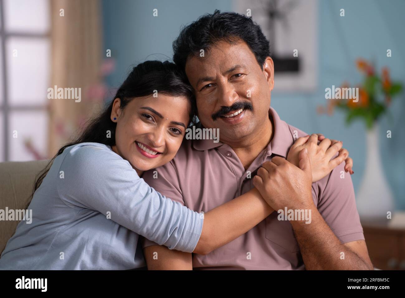 Happy loving daughter hugging or embracing her father by looking camera ...