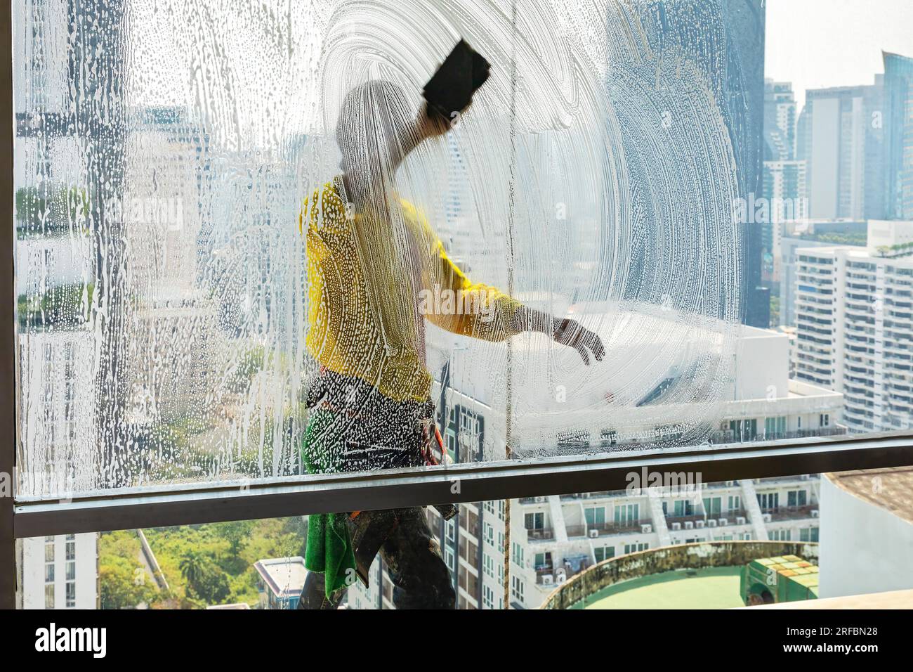 Thai window cleaner working on high rise building overlooking Sukhumvit ...