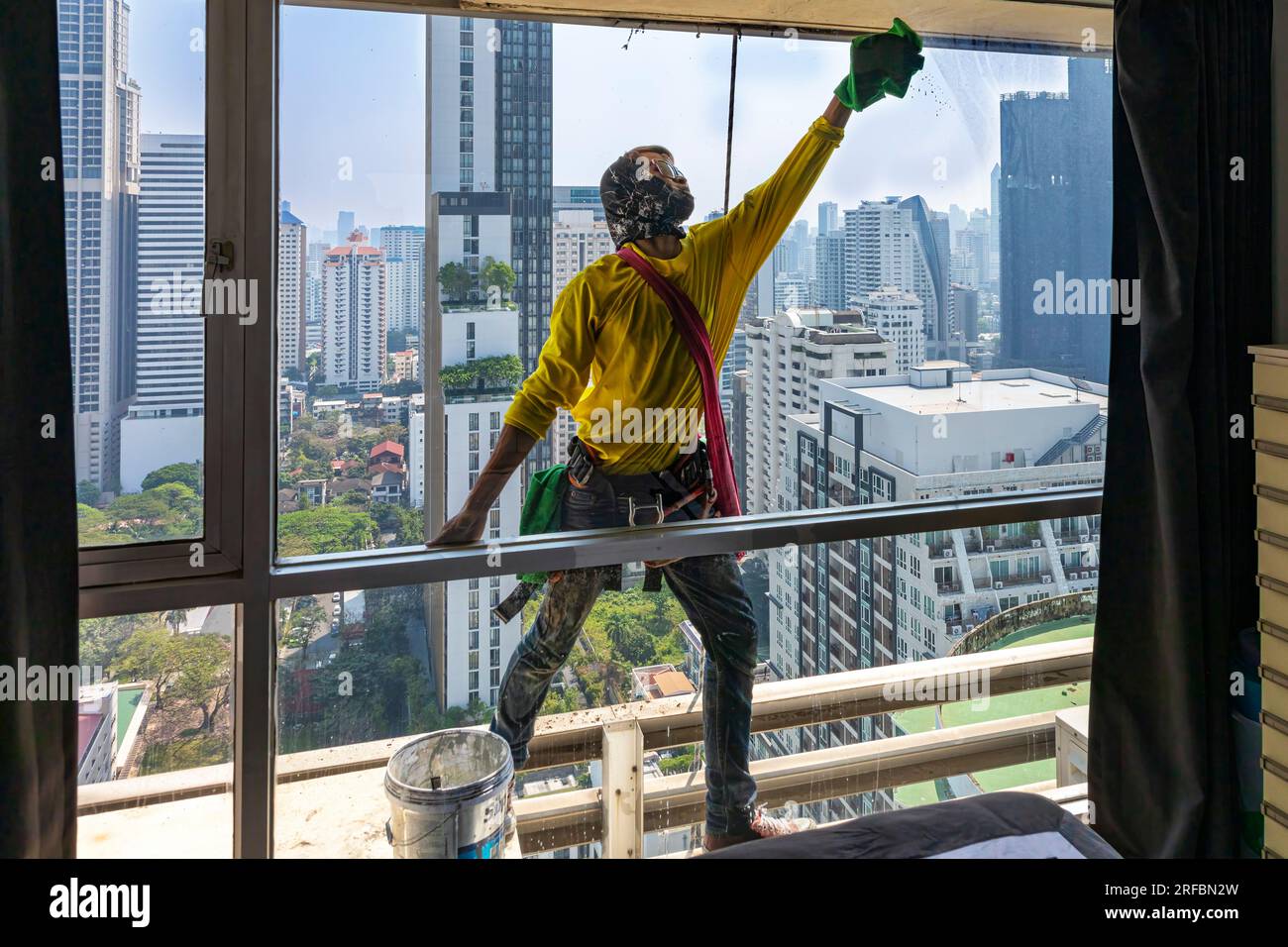 Thai window cleaner working on high rise building overlooking Sukhumvit ...