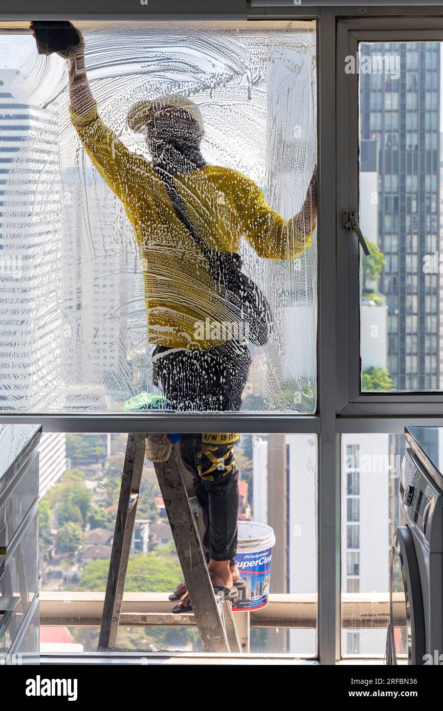 Thai window cleaner working on high rise building overlooking Sukhumvit ...