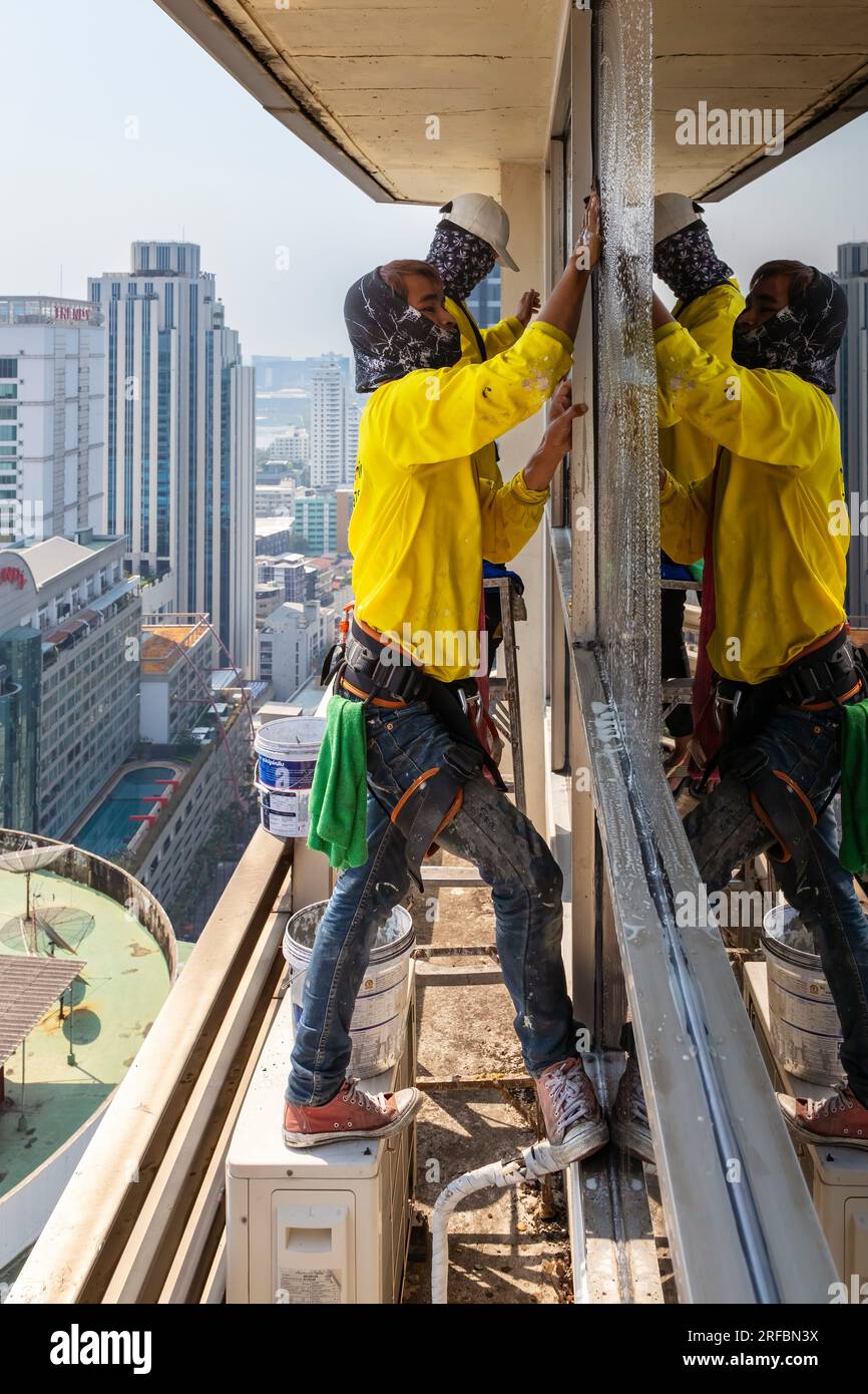 Thai window cleaner working on high rise building overlooking Sukhumvit ...