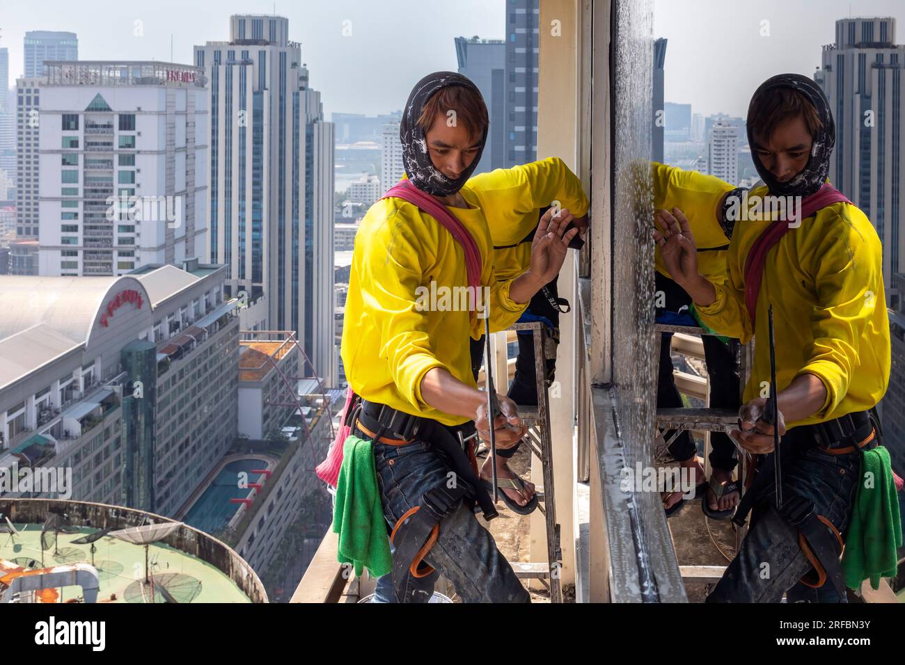 Thai window cleaner working on high rise building overlooking Sukhumvit ...
