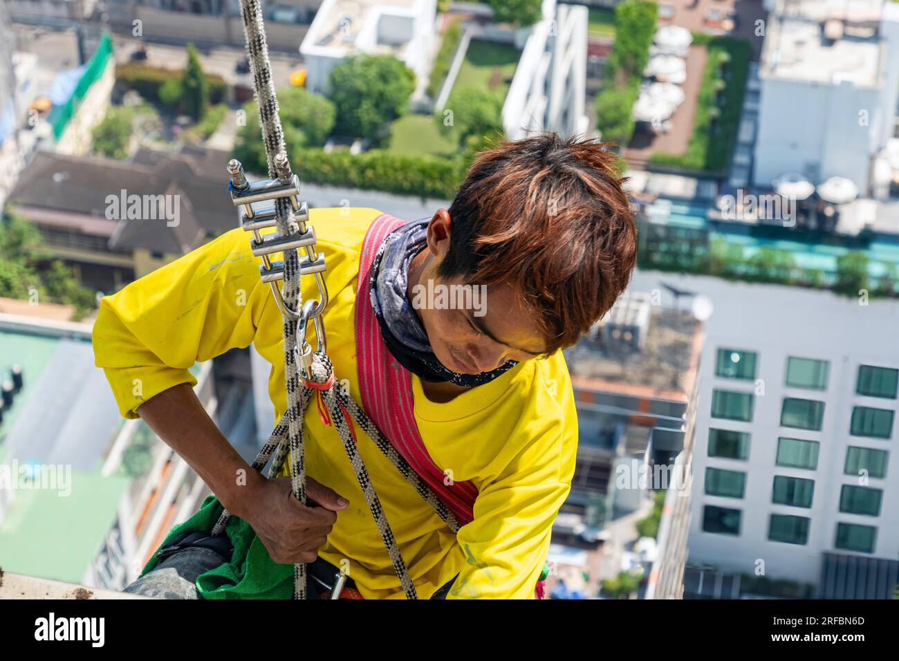 Thai maintenance worker abseiling outside high rise building, Sukhumvit ...