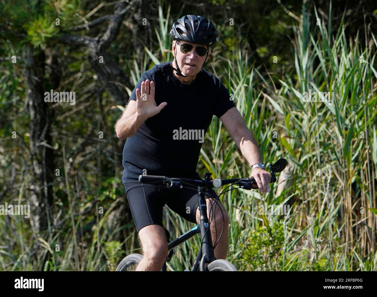 President Joe Biden rides a bike on a path at Gordons Pond in Rehoboth ...