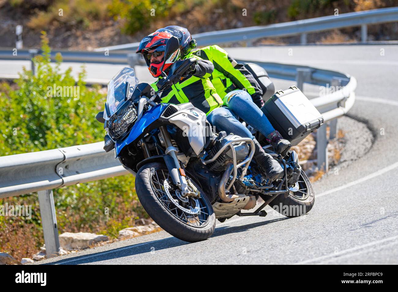Motorcycle rider taking a curve in the foreground, with a background of ...