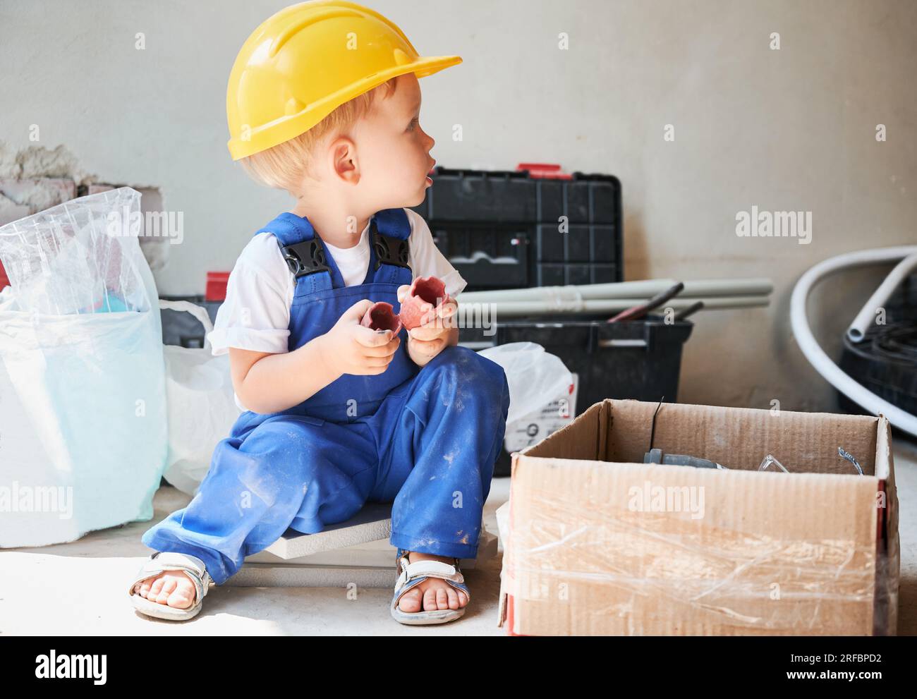 Cute little boy sitting on the floor near cardboard box with tools and ...