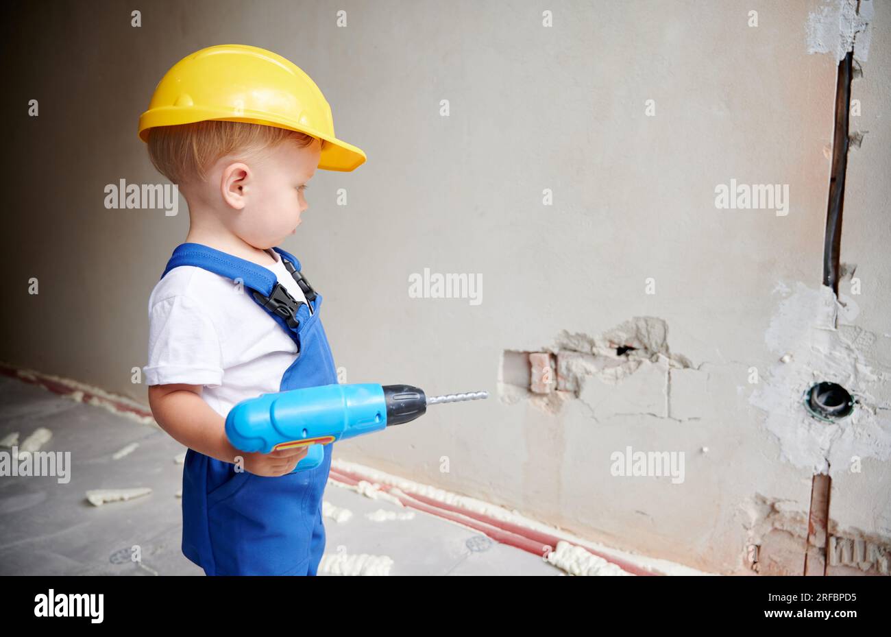Baby boy construction worker with toy electric drill looking at the ...