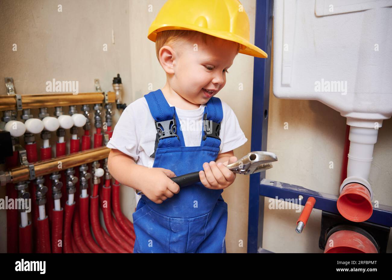 Baby boy looking at construction tool and smiling while standing near ...