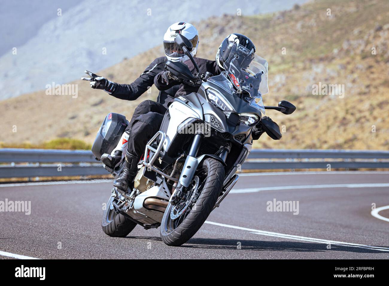 Motorcycle rider taking a curve in the foreground, with a background of ...