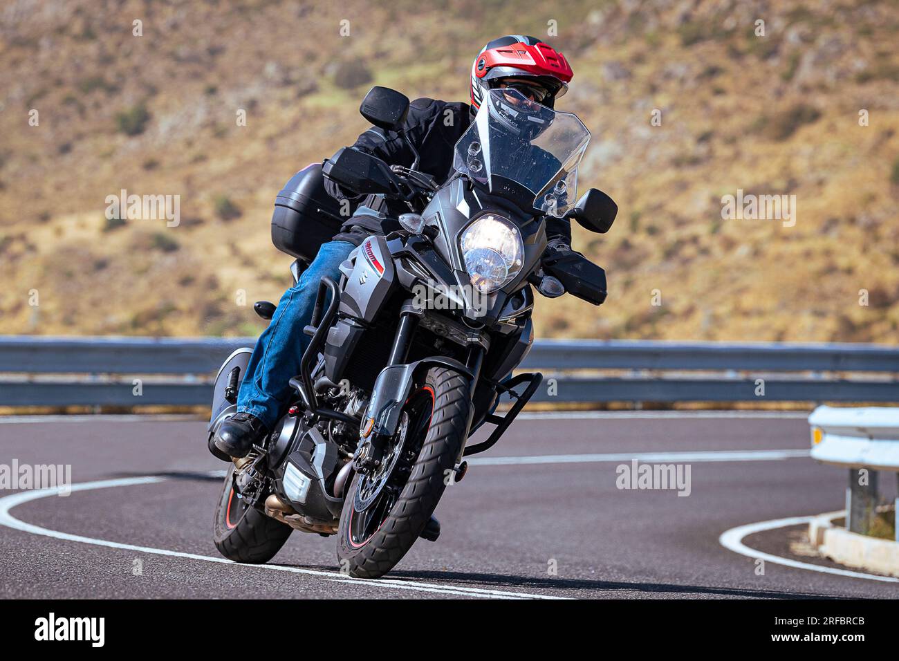 Motorcycle rider taking a curve in the foreground, with a background of ...