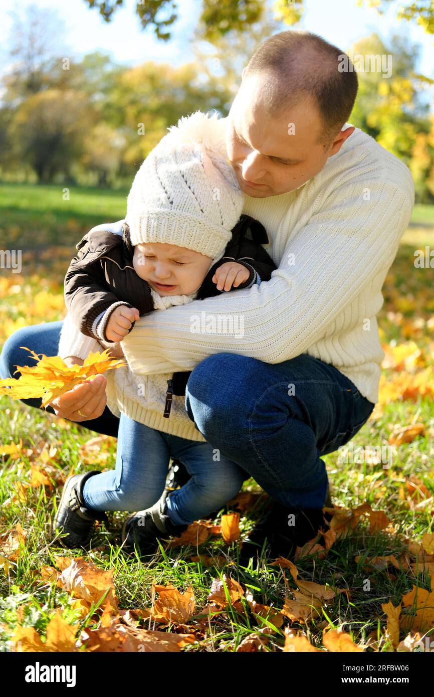 Family weekend in autumn park. The father shows the little son yellow ...