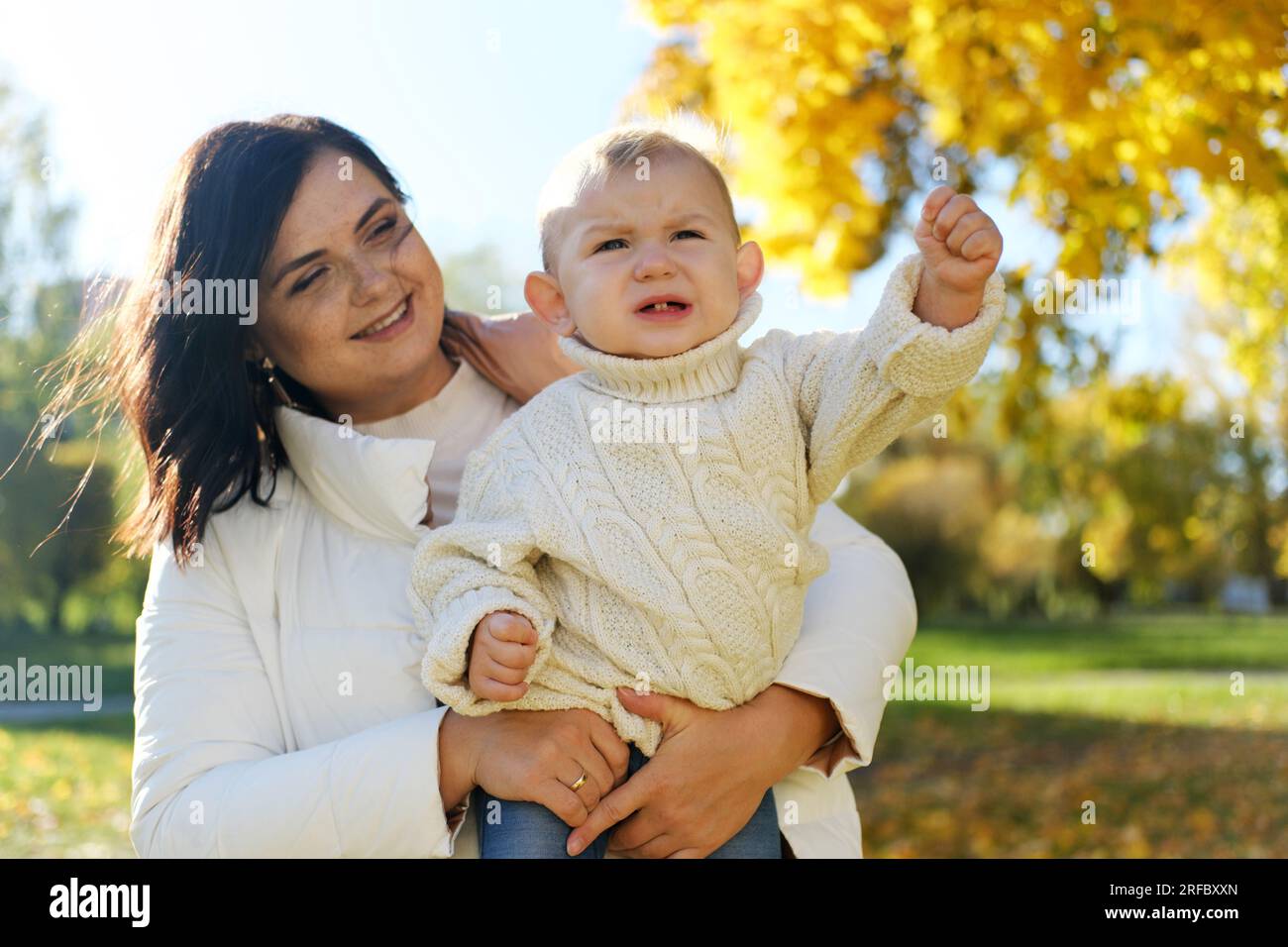 Young stylish mother holds the child in her arms, hugs in an autumn ...