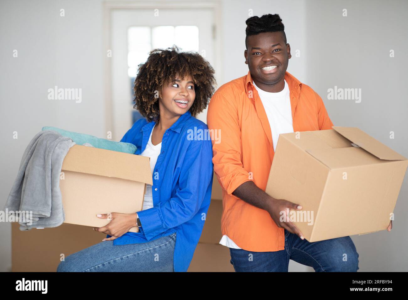 Home relocation. Happy black couple carrying carton boxes in their new house Stock Photo - Alamy