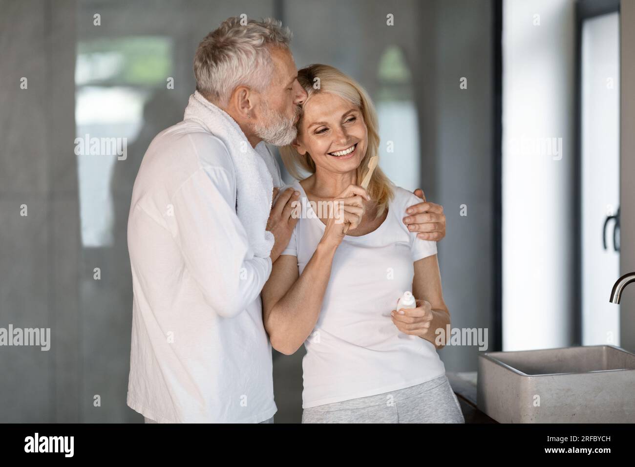 Happy Mature Couple Brushing Teeth In Bathroom, Loving Man Kissing His ...