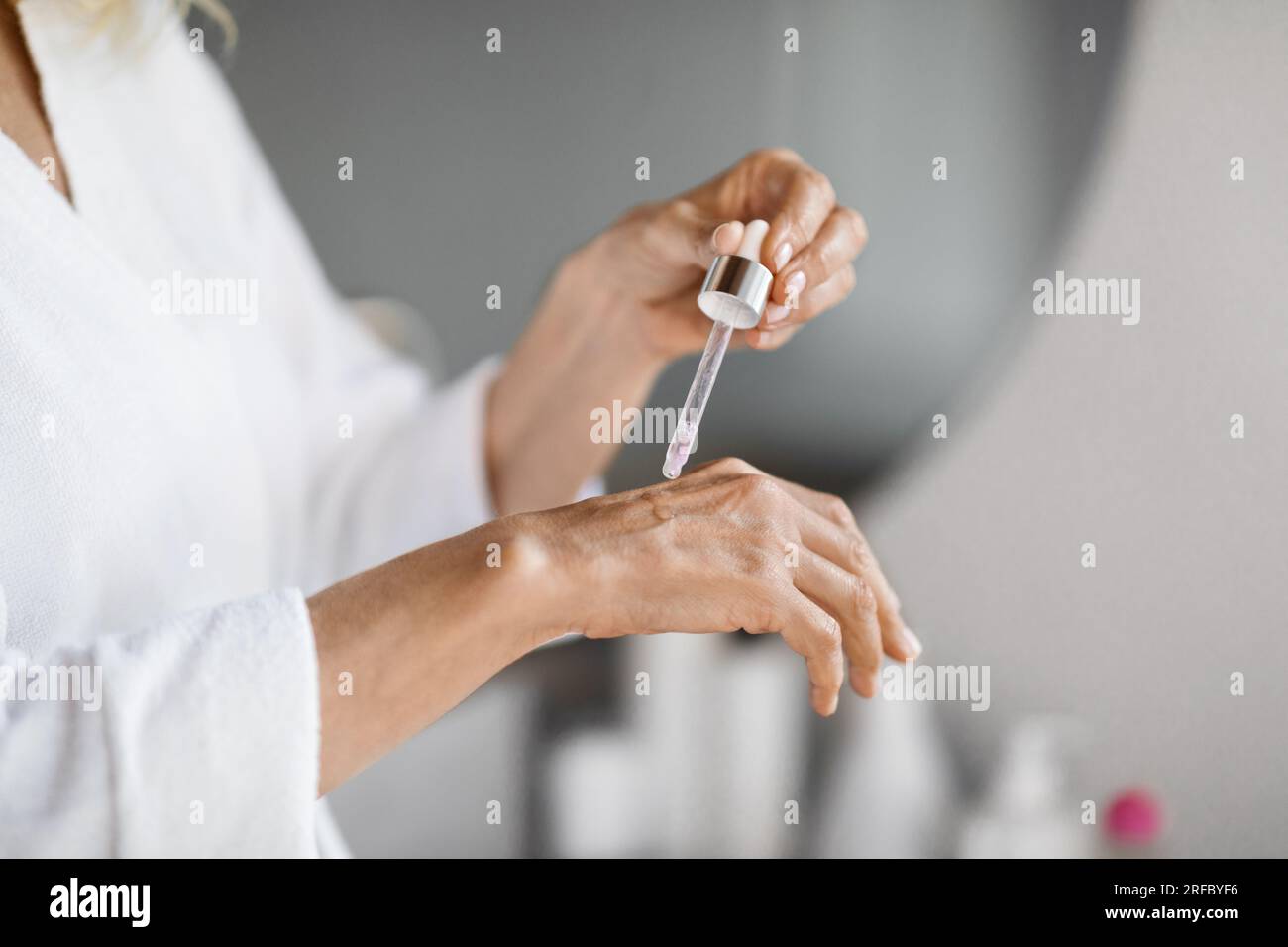 Mature Woman Applying Moisturusing Serum On Hand With Dropper Stock ...
