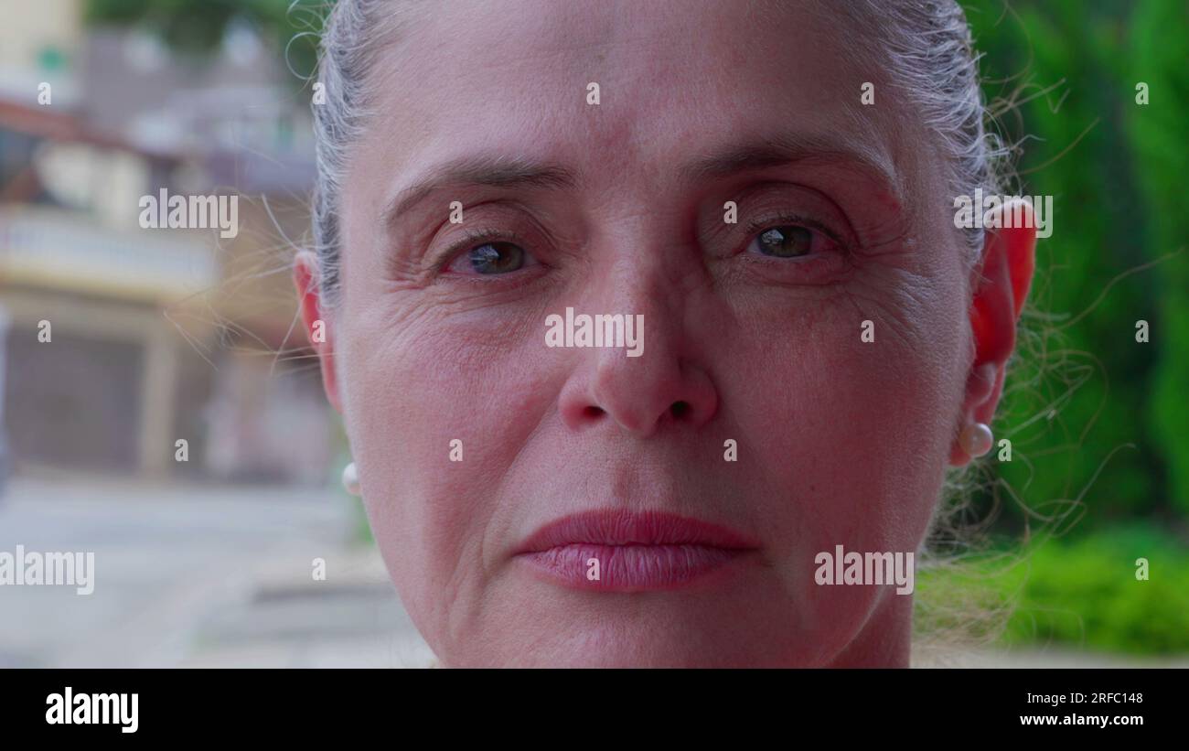 One serious mature woman standing in street portrait face close-up ...