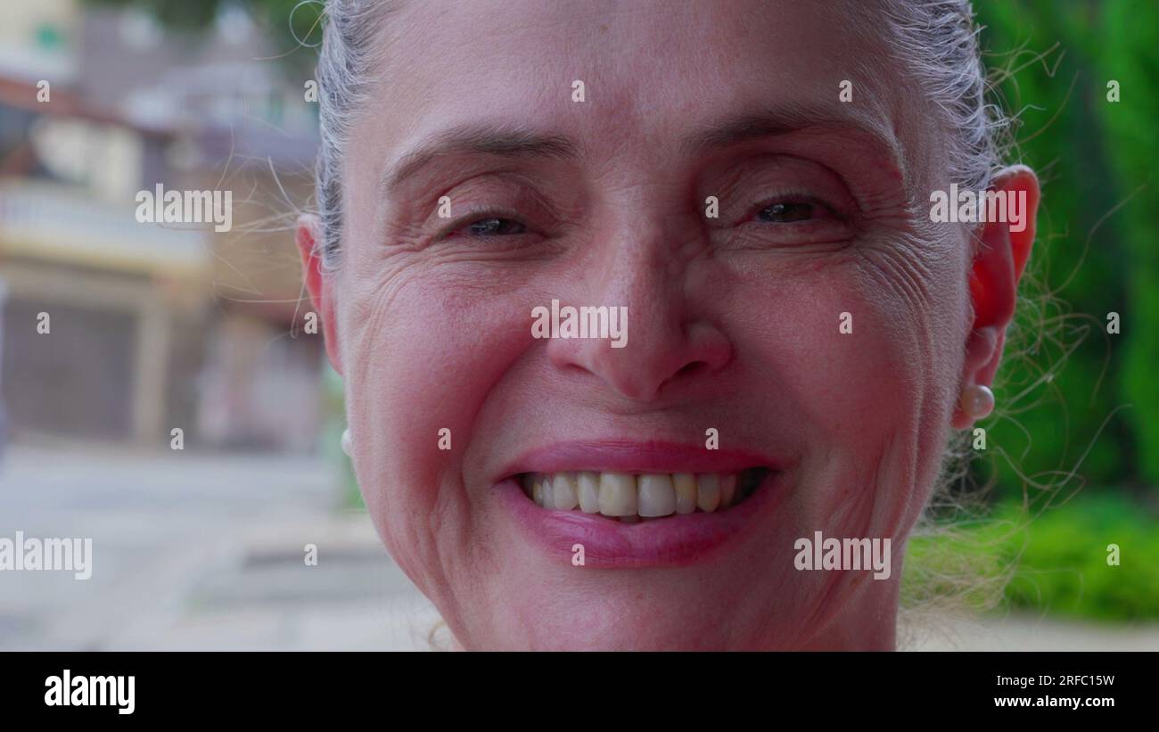 Mature woman cracking a smile feeling happiness standing outside in ...