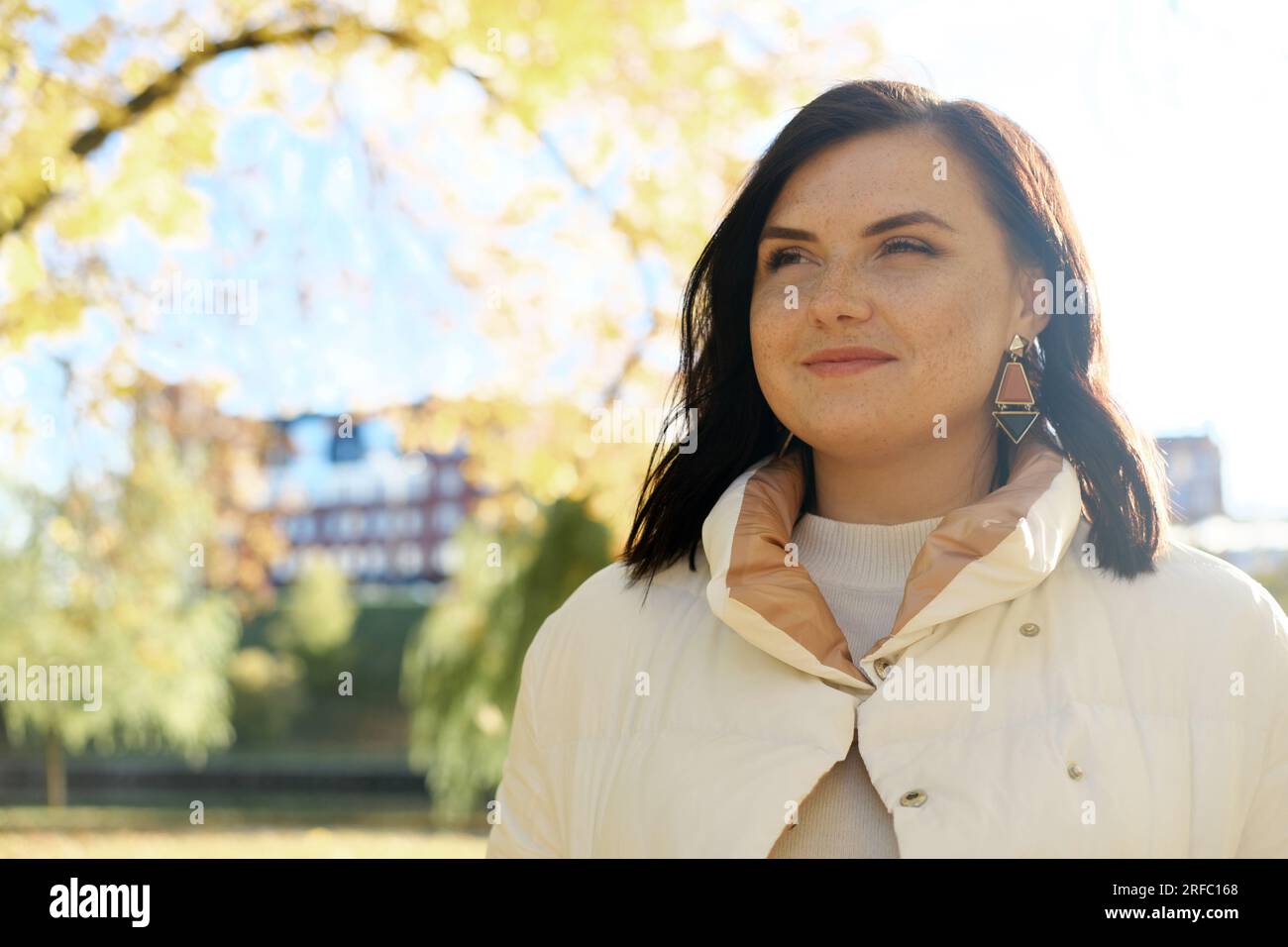 Beautiful brunette woman with freckles on her face smiles and looks ...