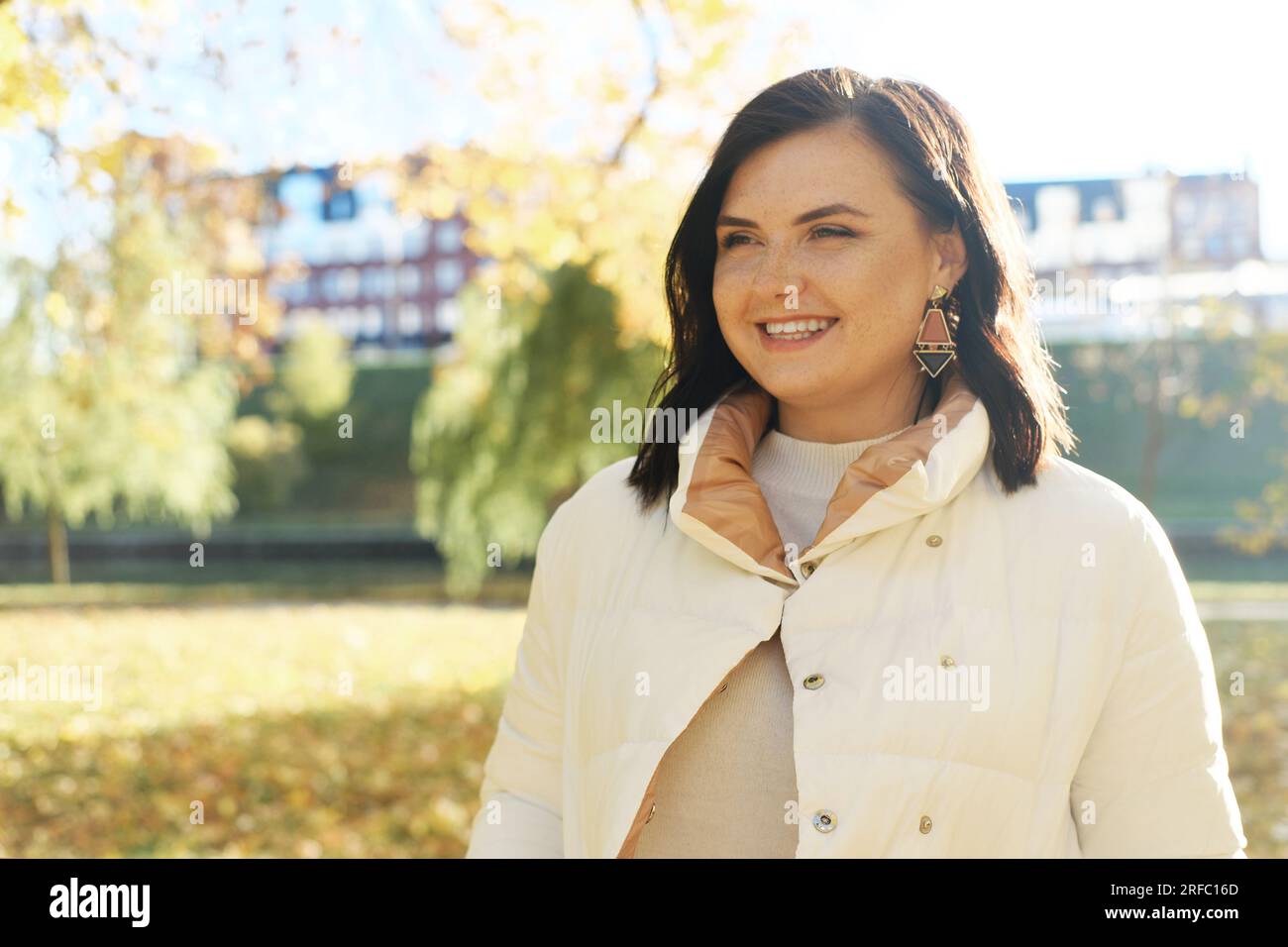Beautiful brunette woman with freckles on her face smiles and looks ...