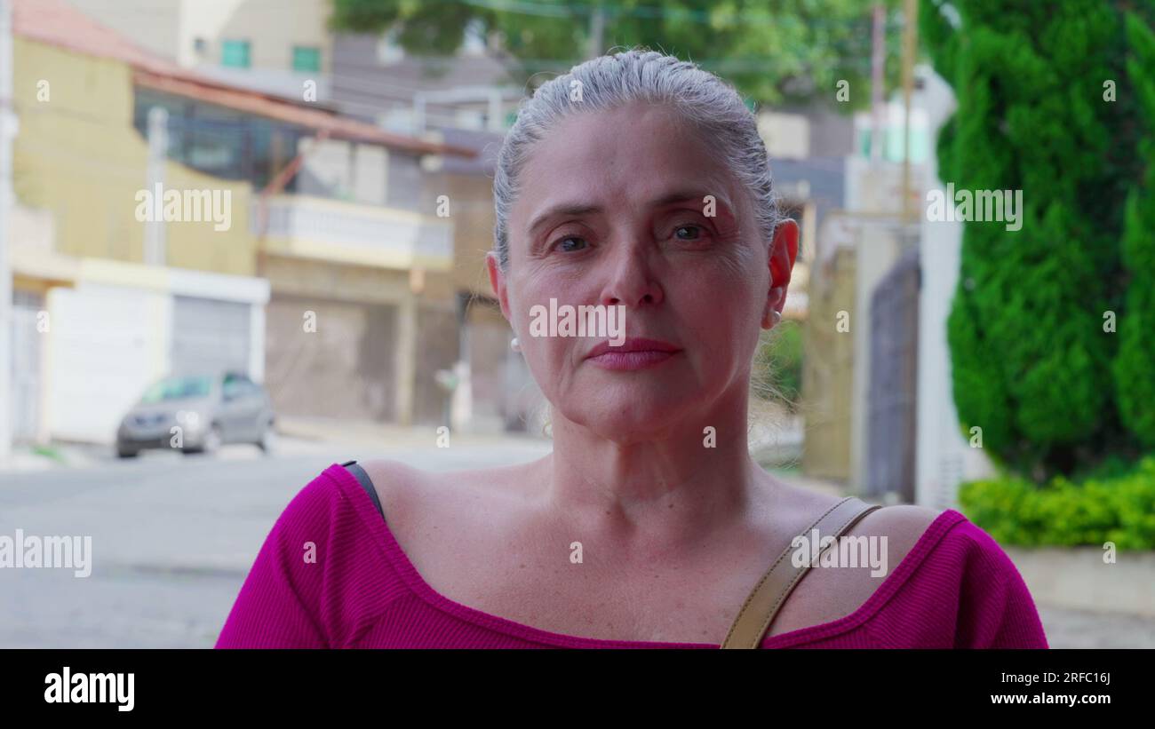 Mature casual woman portrait face standing in street with stern serious ...