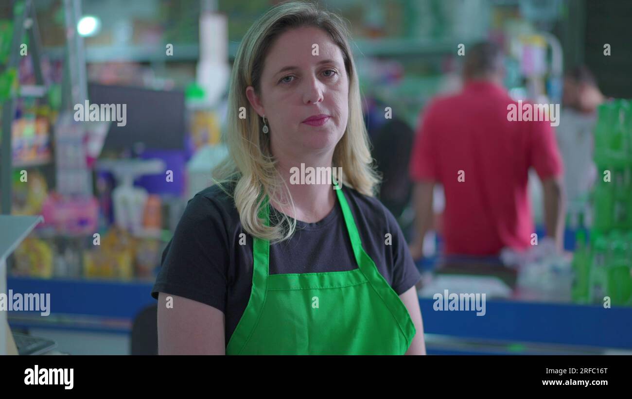 Portrait of a female employee of supermarket cashier at checkout with ...
