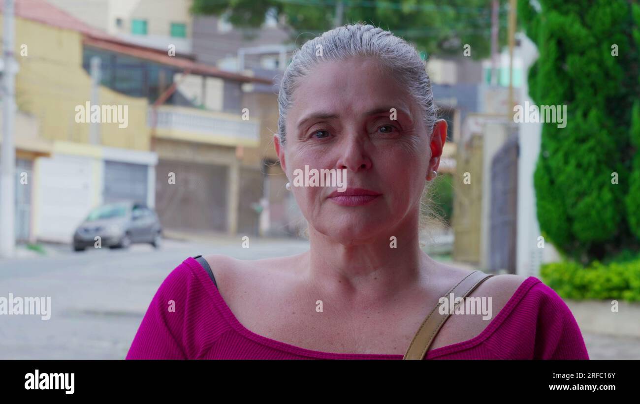 Mature casual woman portrait face standing in street with stern serious ...
