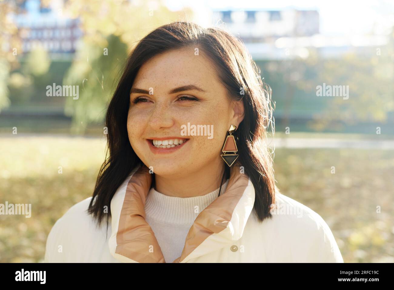 Beautiful brunette woman with freckles on her face smiles and looks ...