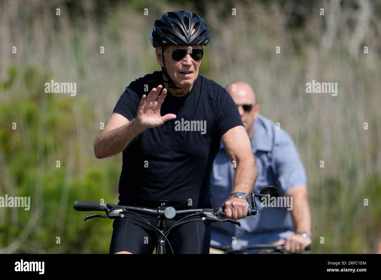 President Joe Biden rides a bike on a path at Gordons Pond in Rehoboth ...