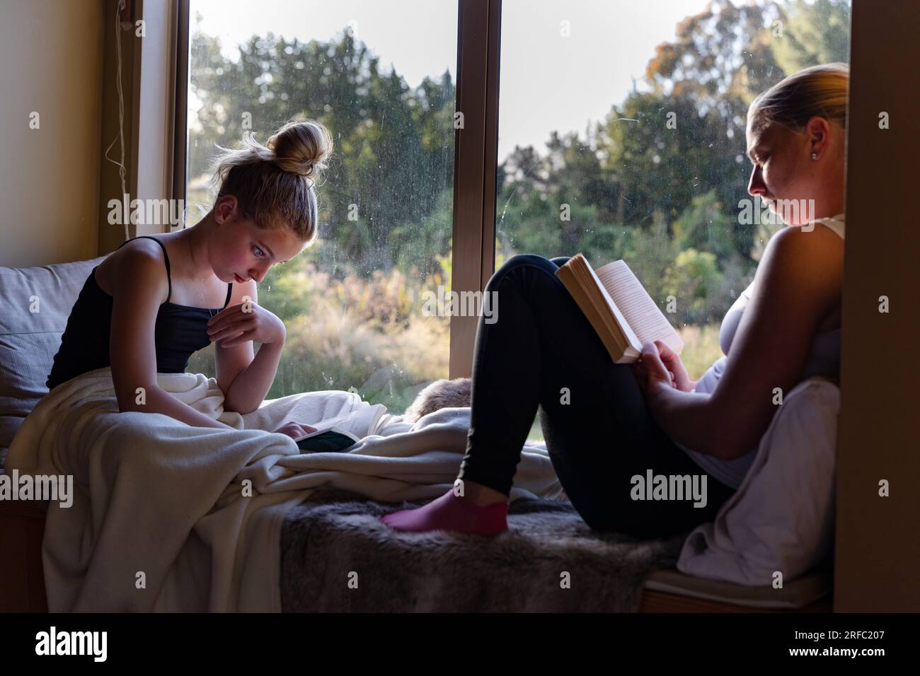 A family relax in a woodland cabin window seat in the Manapouri region ...