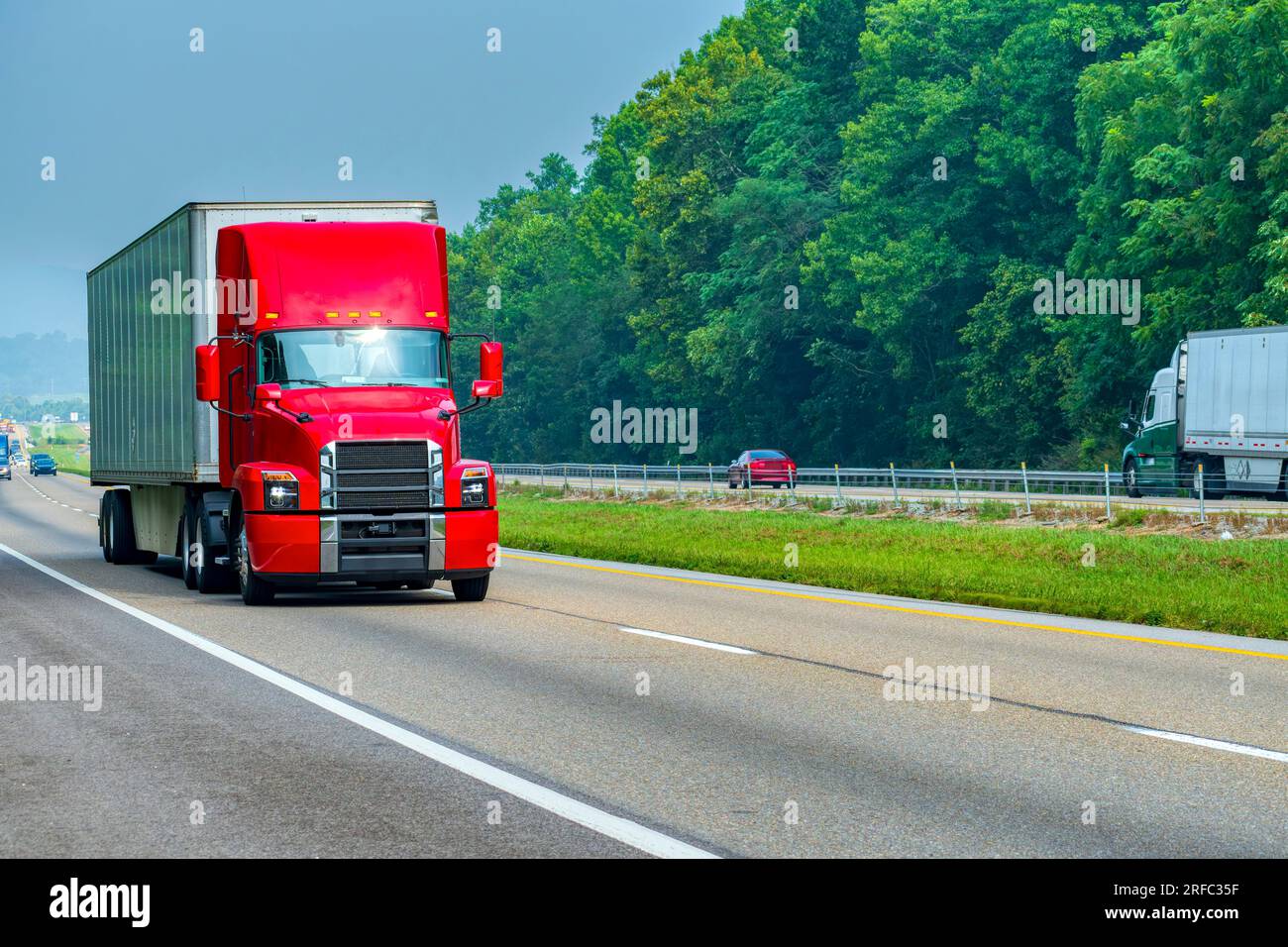 Horizontal shot of a modern red semi truck on the interstate highway ...