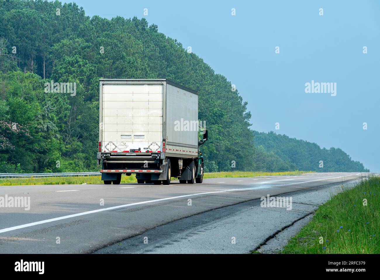 Horizontal side rear view shot of an eighteen wheeler going down the ...