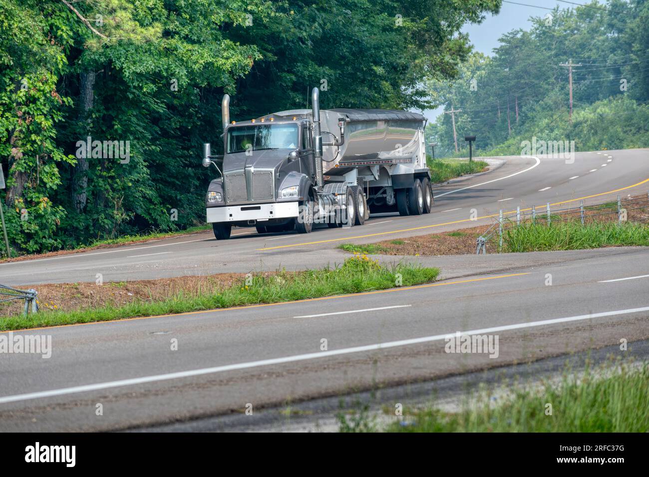 Horizontal shot of an eighteen wheeler traveling on a rural secondary ...