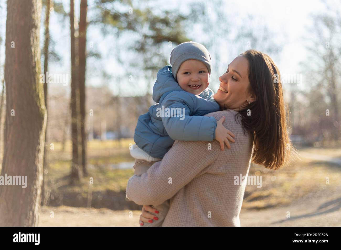 Happy family outdoor. Mother embracing her child outdoor. Mom lifting in air little toddler ...