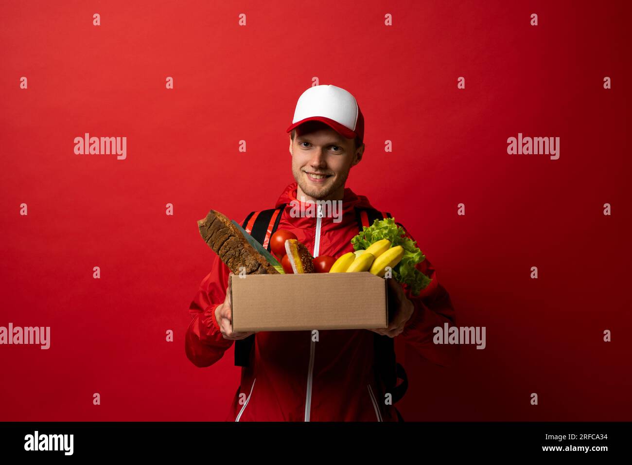 Deliver man worker in red uniform handling box of food, fruit ...